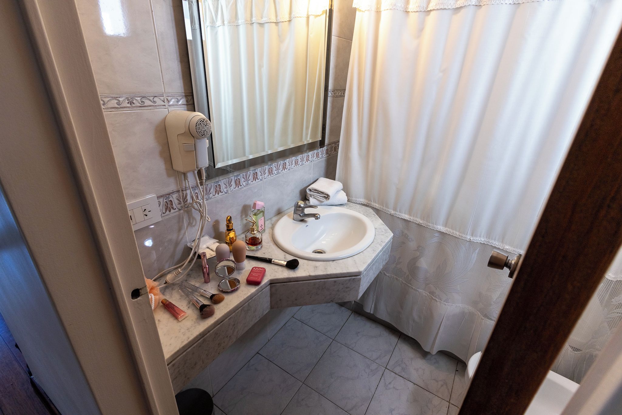 Casa de banho com lavatório, espelho e artigos de higiene pessoal.