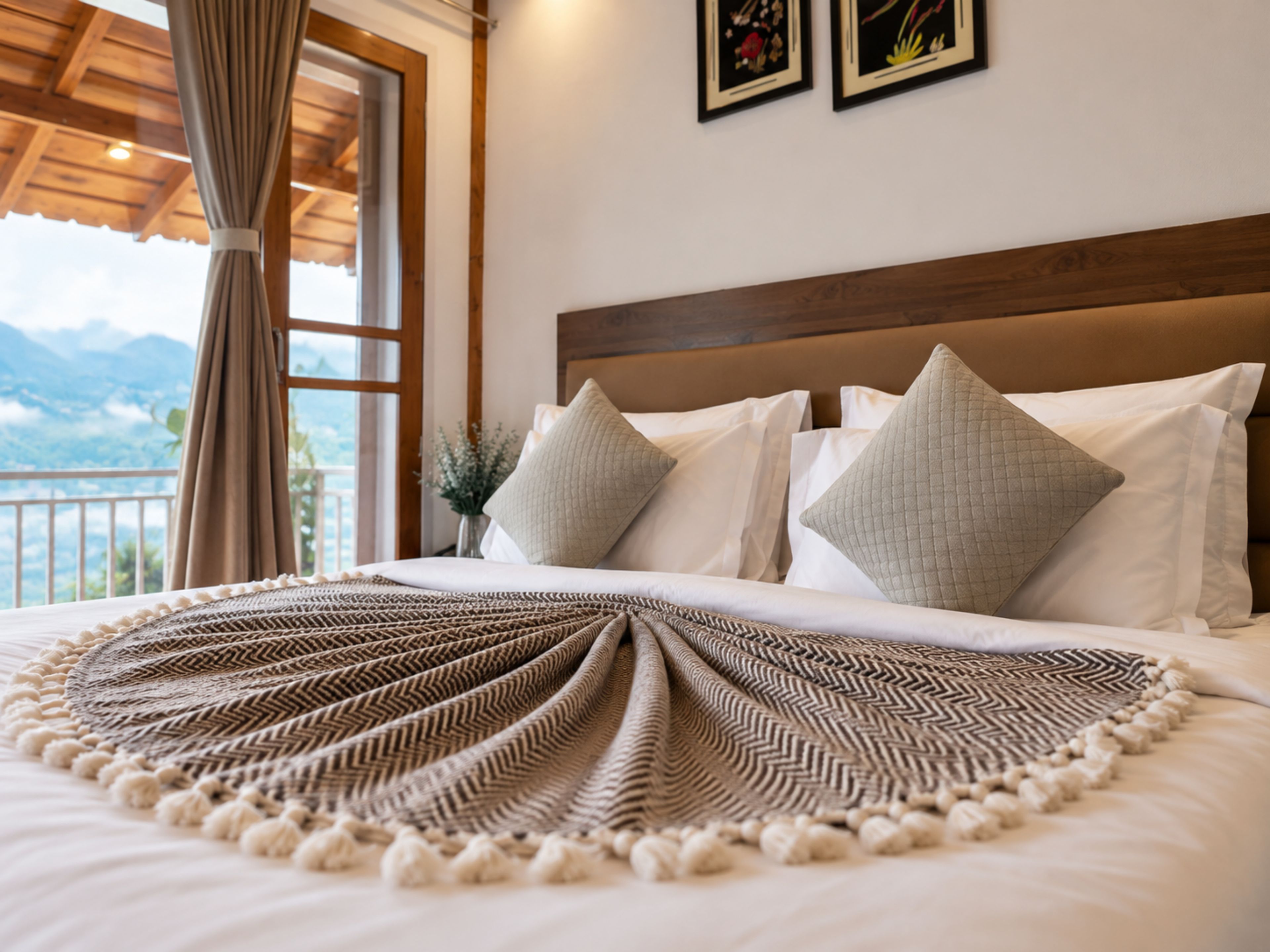 Cama com manta estampada, cabeceira de madeira e vista para montanhas pela janela.