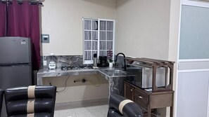 Cozinha compacta com geladeira, fogão, pia e micro-ondas.