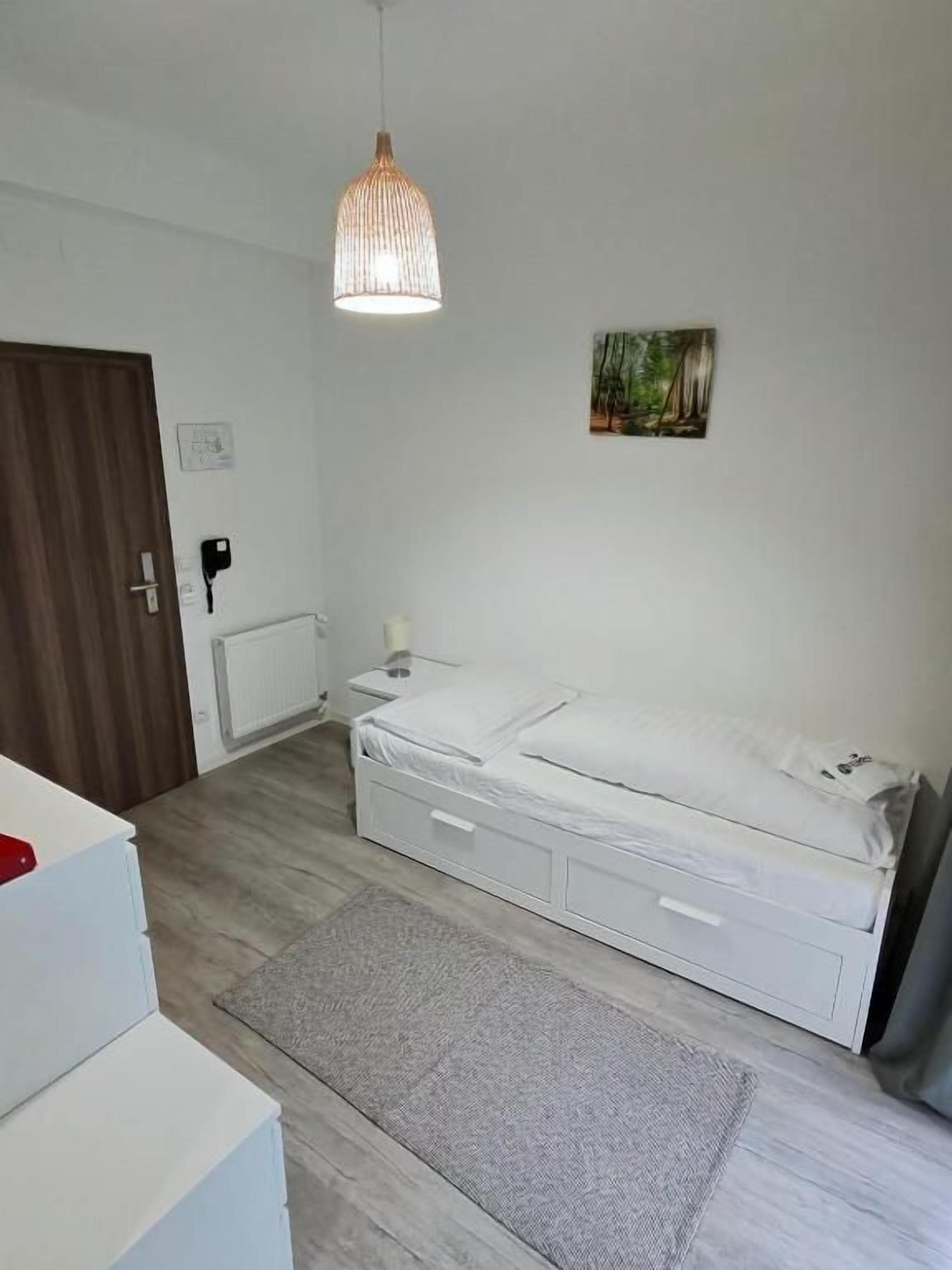 Quarto com cama, mesa de cabeceira e luminária pendente.