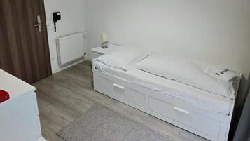 Quarto com cama, mesa de cabeceira e luminária pendente.