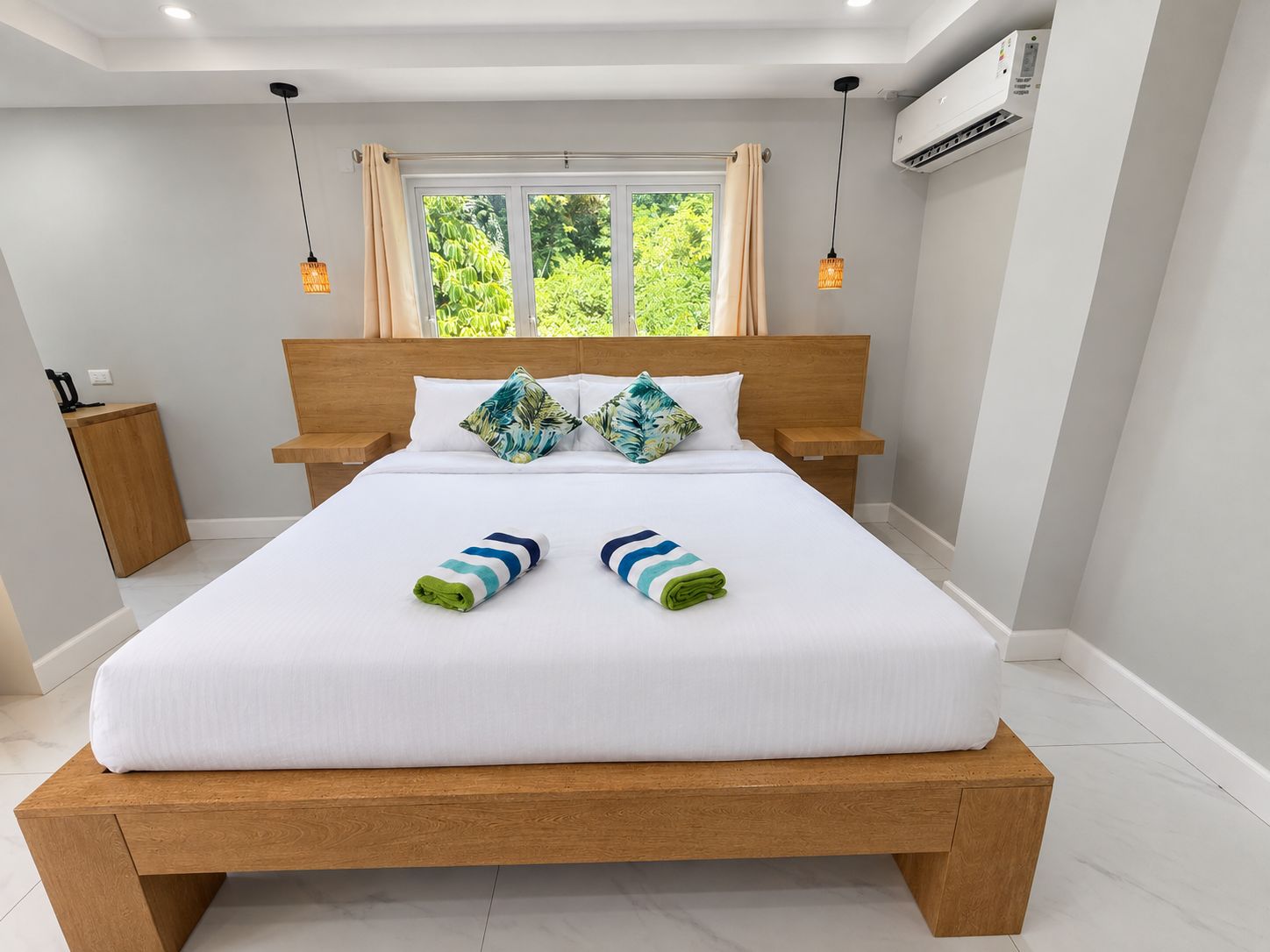 Quarto moderno com uma cama grande, cabeceira de madeira, duas mesas de cabeceira, janela com cortinas e aparelho de ar condicionado.