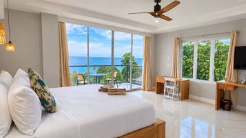 Quarto espaçoso com uma cama grande, ventilador de teto, escrivaninha e vista para o mar.