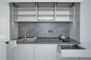Cozinha com pia embutida, bancada e gaveta com utensílios.