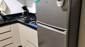 Cozinha equipada com geladeira de aço inoxidável, micro-ondas e fogão a gás.