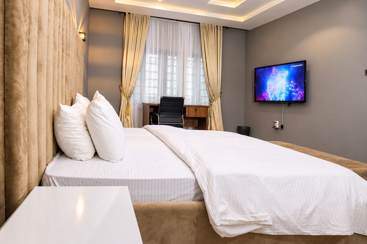 Quarto de hotel com duas camas, televisão e escrivaninha.