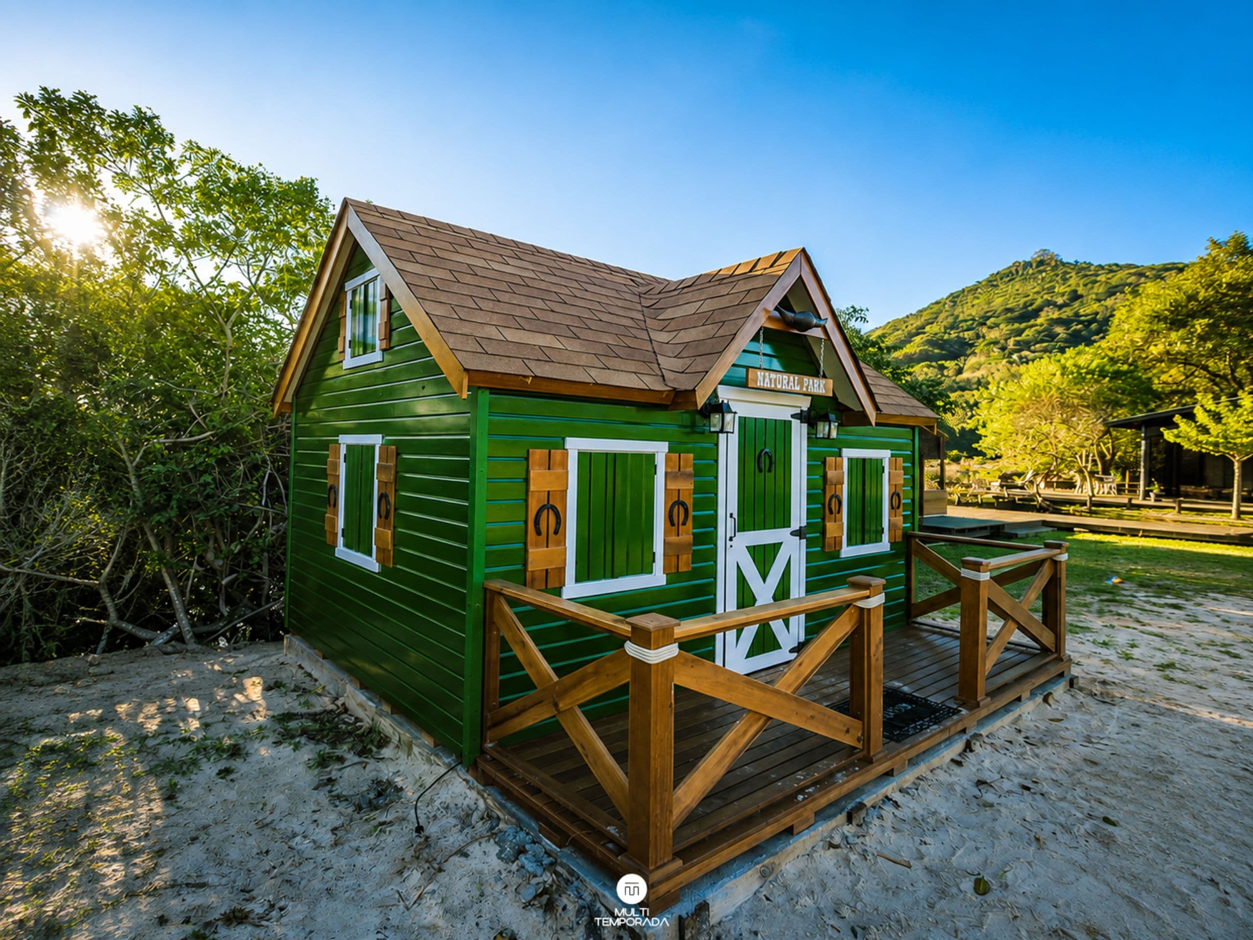 Uma cabana de madeira verde com varanda, uma placa indicando 'Natural Park' e montanhas ao fundo.