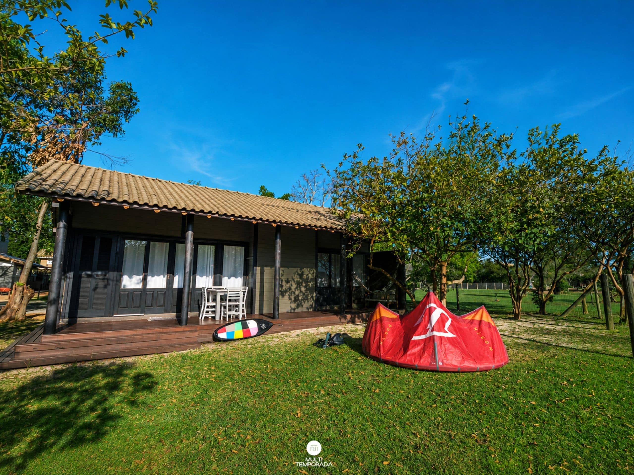 Uma casa com telhado de cerâmica, varanda coberta e gramado.