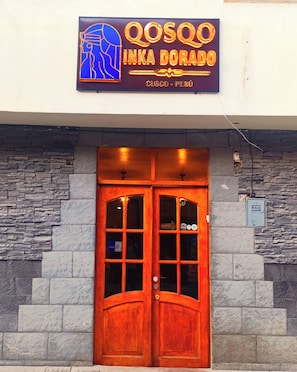 Entrada de um edifício com uma placa que diz 'QOSQO INKA DORADO Cusco - Peru'.