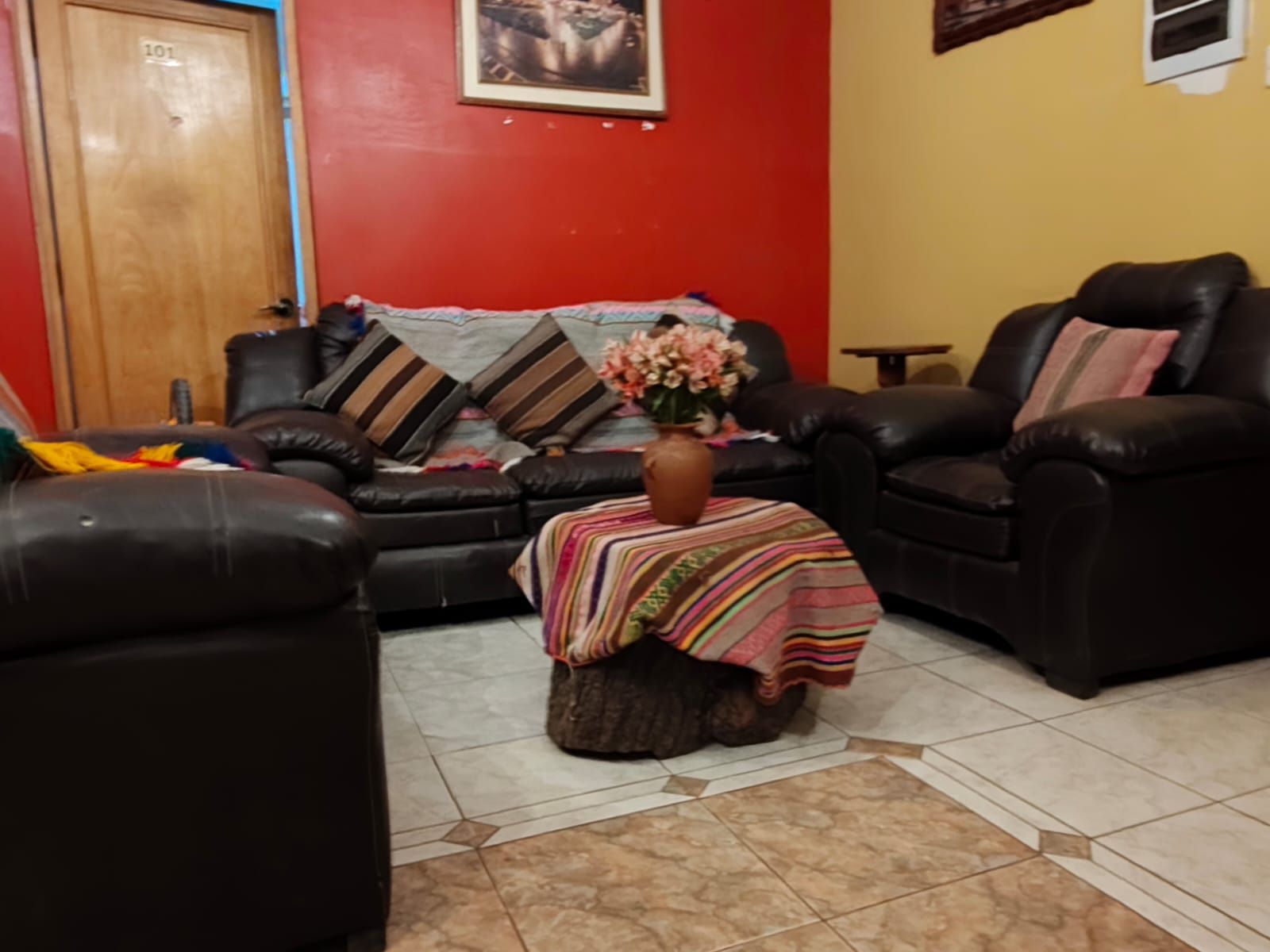 Uma sala de estar com sofá, mesa de centro e um vaso de flores.