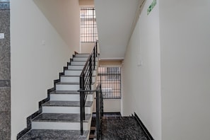 Uma escadaria com guarda-corpos pretos e degraus de mármore que levam a um patamar.