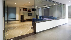 Uma área de recepção moderna com divisória de vidro, um sofá azul, uma lareira e uma placa indicando 'Townhouse'.