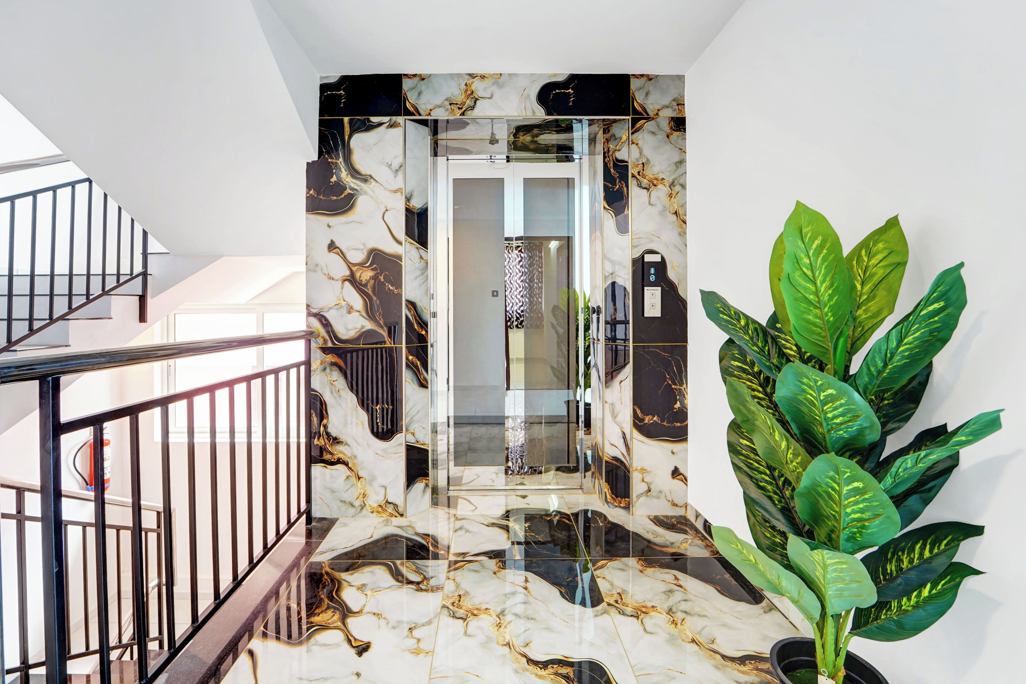 Um interior moderno com piso de mármore, um elevador de vidro e uma planta em vaso.