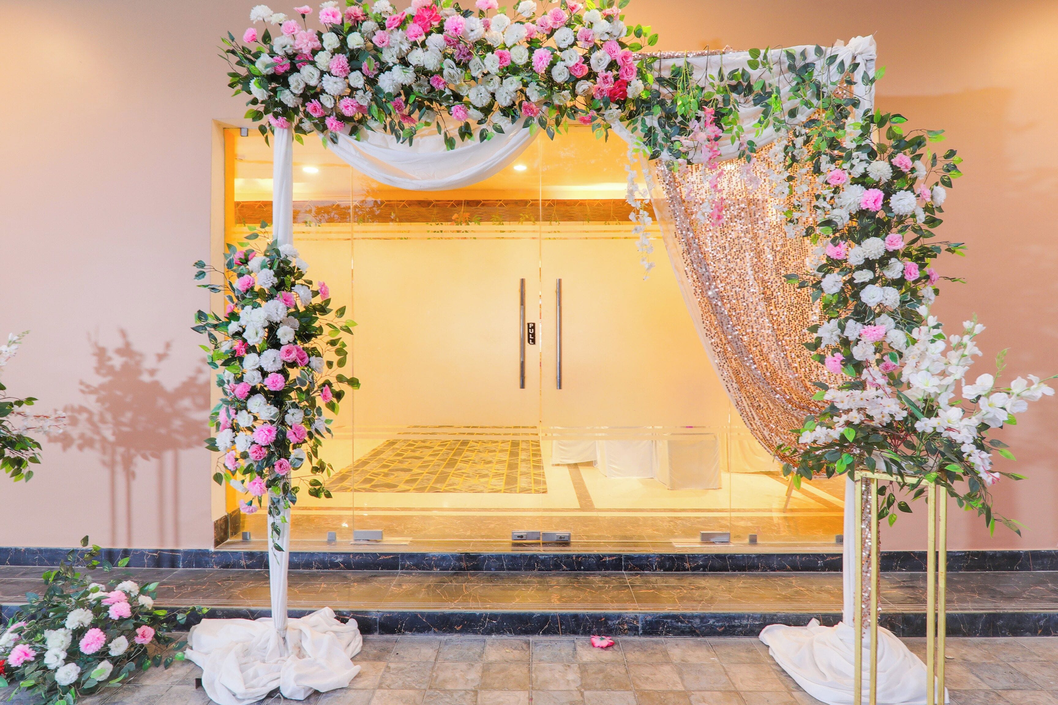Um arco de flores que dá acesso a um quarto com cama e porta.
