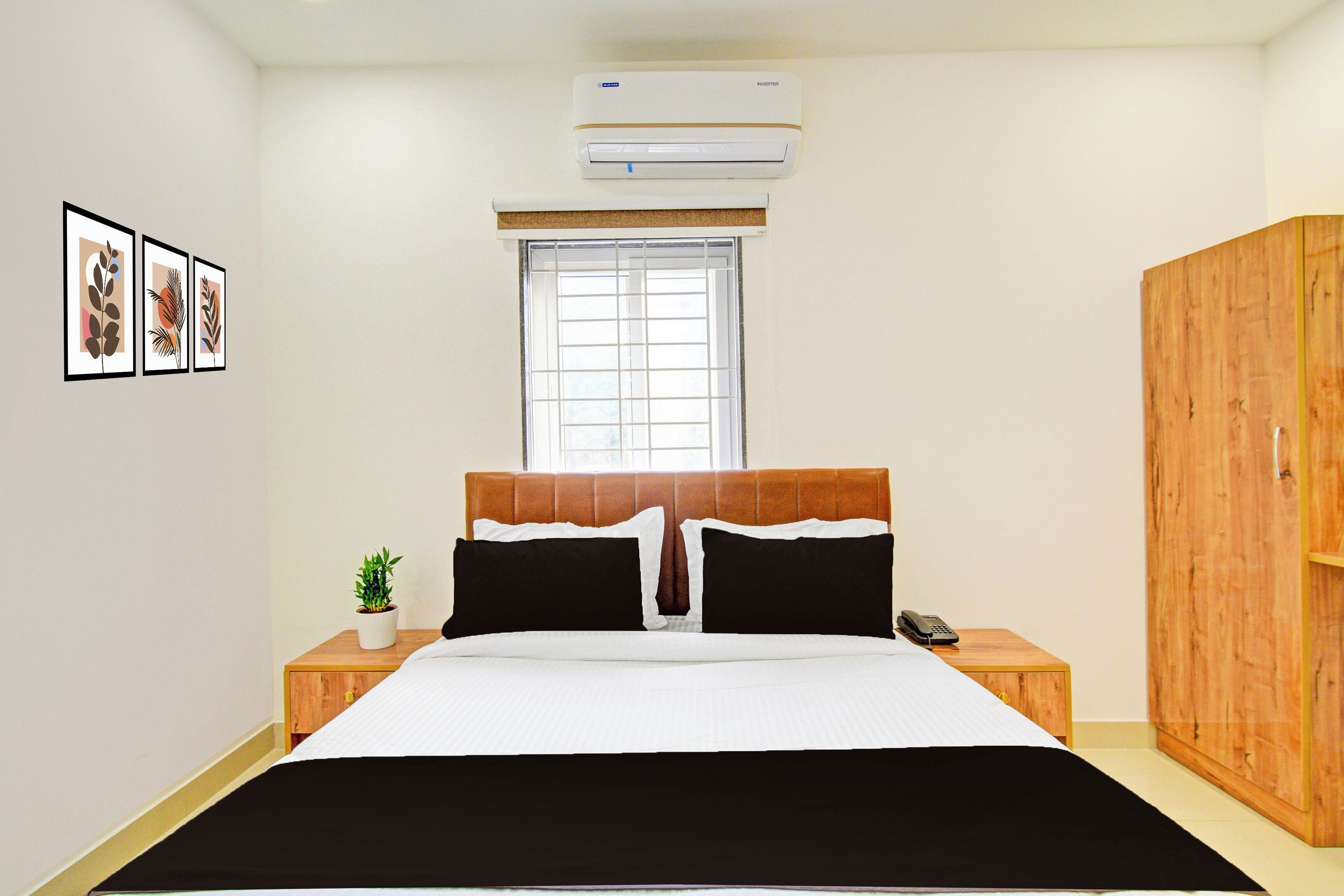 Quarto com cama, janela, ar-condicionado, mesa de cabeceira com telefone e guarda-roupa de madeira.