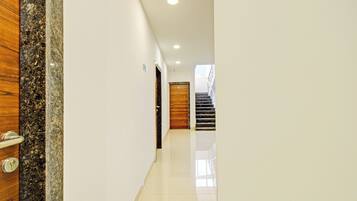 Corredor com porta de madeira e escada que dá acesso a um andar superior.