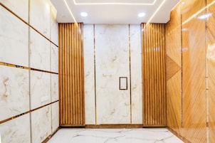 Um interior moderno com paredes de mármore, painéis de madeira e iluminação embutida no teto.