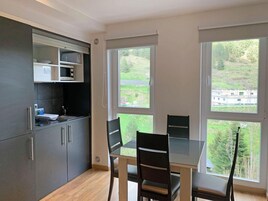 Uma cozinha moderna com armários escuros e um espaço de refeições com mesa e cadeiras.
