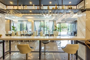 Um hall de hotel moderno com bar central, áreas de estar e vista para o exterior.