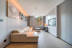 Uma sala de estar moderna com um sofá seccional, um espaço de jantar com mesa e cadeiras, e uma janela grande que oferece uma vista.