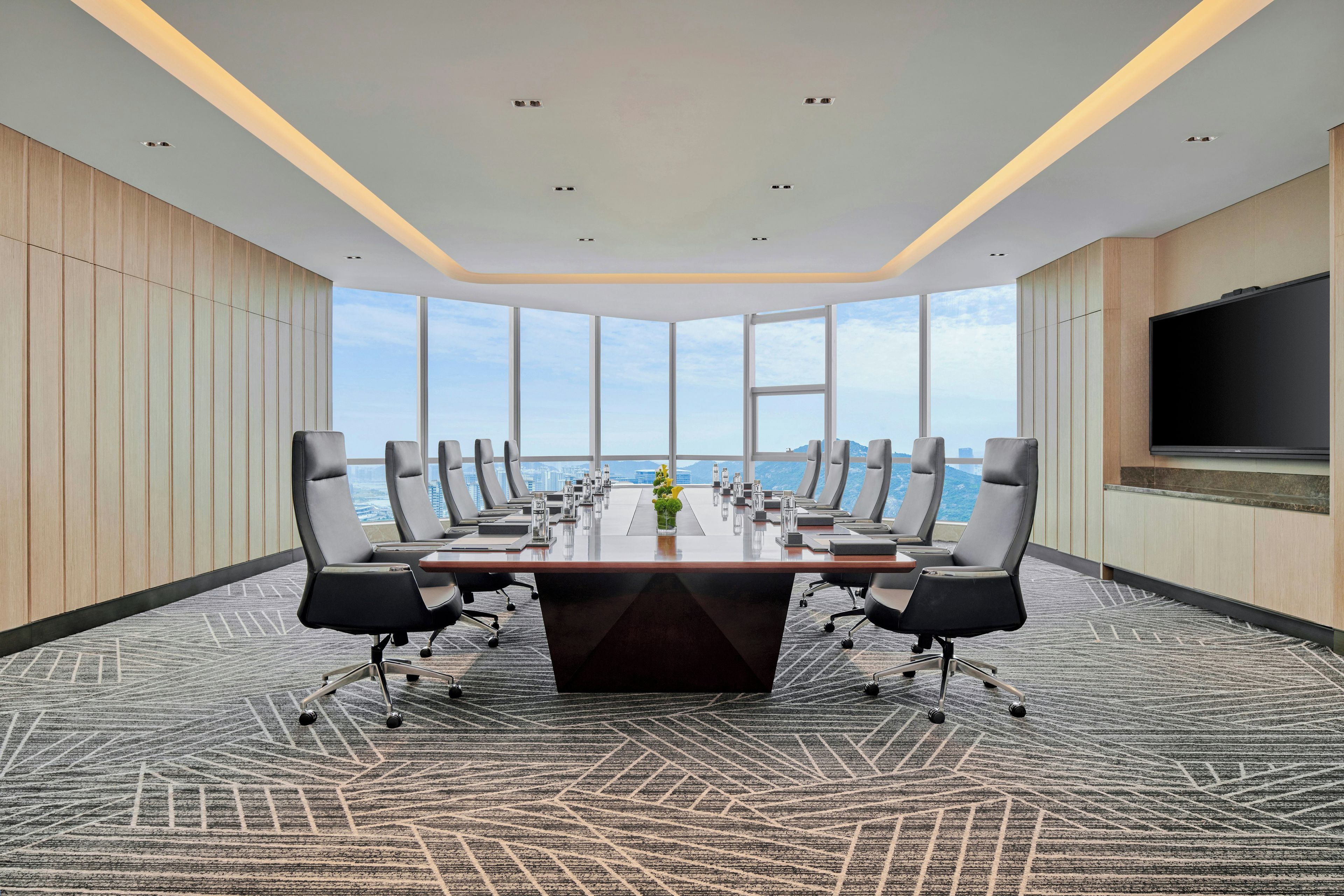 Uma sala de conferências com uma mesa grande, cadeiras e vista para o oceano.