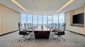 Uma sala de conferências com uma mesa grande, cadeiras e vista para o oceano.