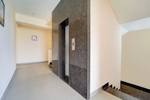 Um corredor com parede de mármore, porta e chão de azulejos.