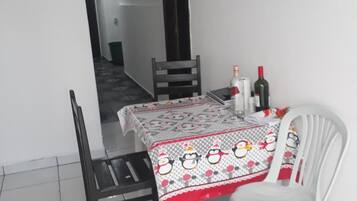 Espaço de refeições com mesa posta para dois, uma cadeira e uma garrafa de vinho.