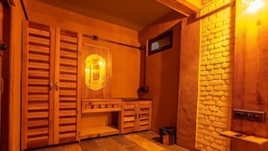 Um interior de madeira com um banco, uma luminária na parede e uma parede de tijolos.