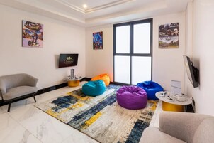 Uma sala de estar moderna com um sofá, poltronas de saco, uma mesa de centro e uma televisão.