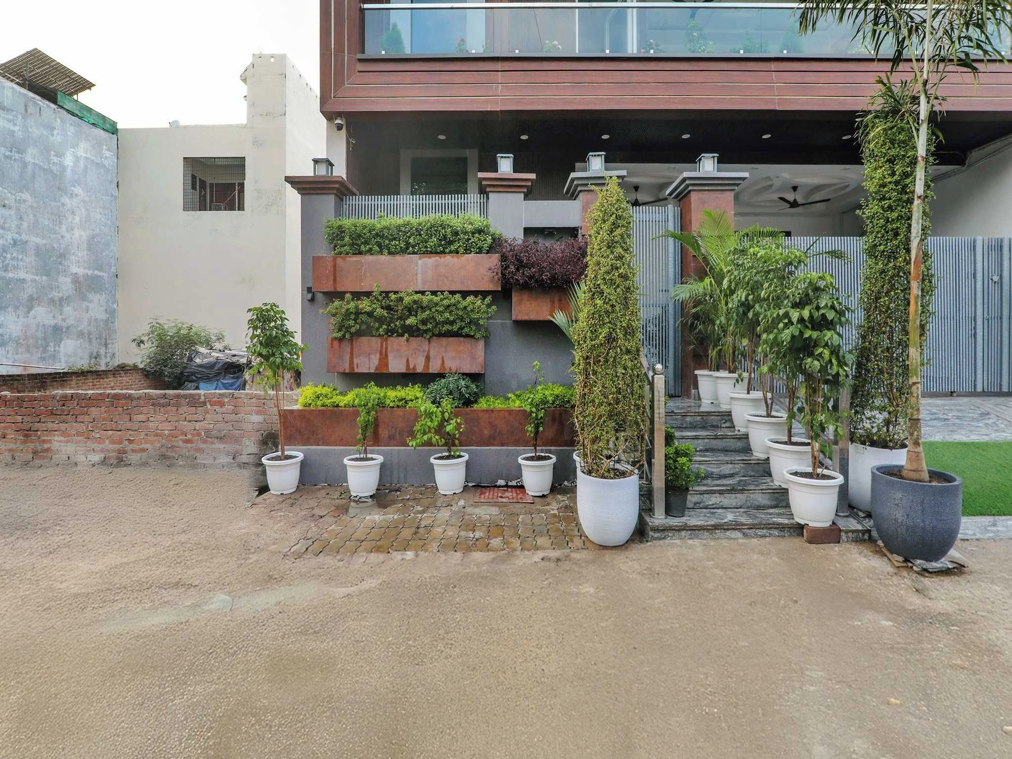 Um edifício moderno com telhado plano, parede de tijolos e uma série de vasos com diversas plantas.