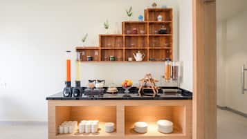 Cozinha com bancada de madeira, espaço para café e prateleira com copos e objetos decorativos.