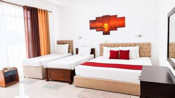 Quarto de hotel com uma cama grande, duas camas menores, uma televisão e um quadro na parede.