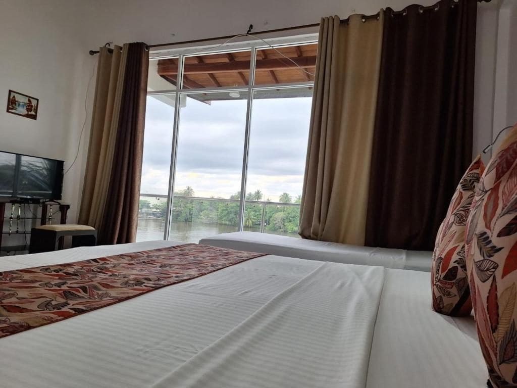 Quarto de hotel com uma cama grande, televisão e vista para o exterior.