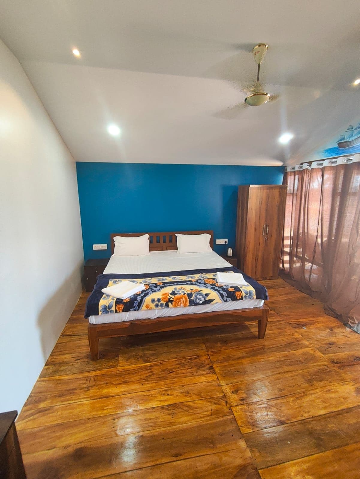 Quarto com cama de madeira, parede azul e guarda-roupa.