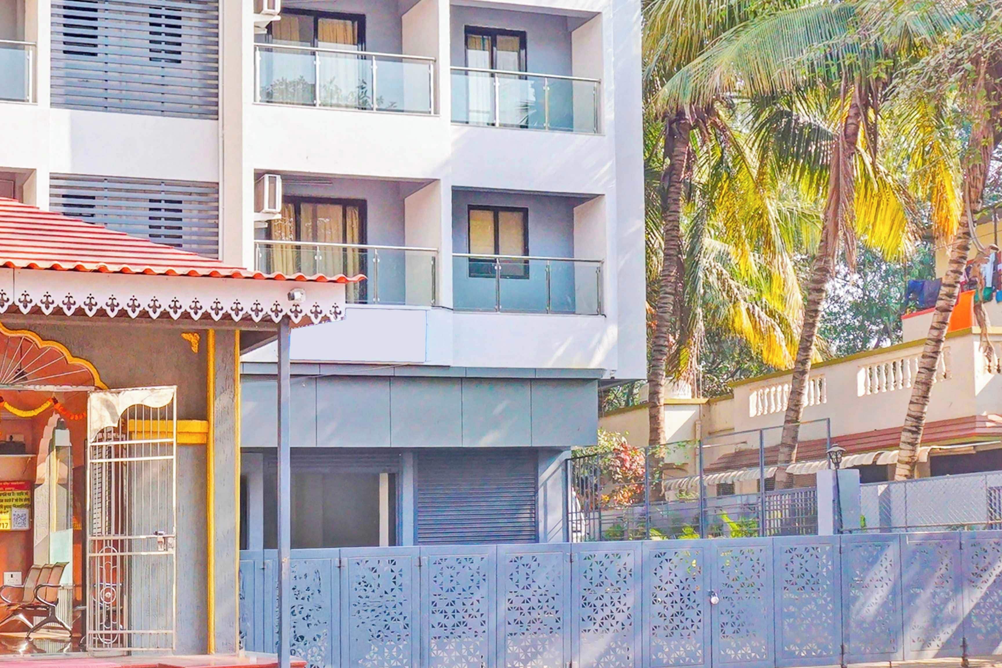 Um edifício com várias andares, varandas, entrada coberta e portão decorativo.