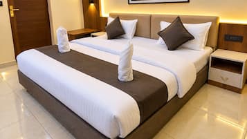 Quarto de hotel com uma cama grande, duas mesas de cabeceira e uma luminária na parede.
