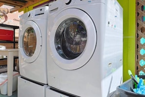 Duas máquinas de lavar roupa de carregamento frontal empilhadas em ambiente comercial.