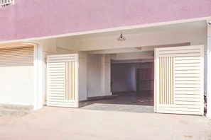 Entrada de um prédio com uma persiana fechada à esquerda e persianas abertas à direita.
