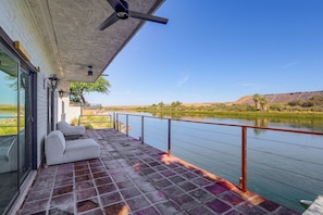 Uma varanda com vista para um rio, um sofá branco e um ventilador de teto.