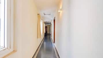 Um corredor comprido e estreito com piso escuro, paredes brancas e teto com iluminação embutida.