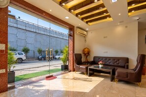 Um saguão de hotel com área de estar, uma janela ampla e vista para a rua.