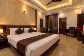 Quarto de hotel com uma cama grande, mesas de cabeceira, uma escrivaninha e uma cadeira.