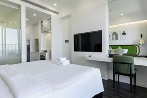 Quarto de hotel com cama, escrivaninha com televisão de tela plana, cadeira e cabeceira verde.