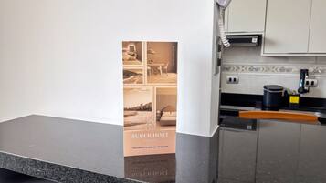 Cozinha com eletrodomésticos modernos, bancada e vista para um quarto com cama e paisagem urbana.
