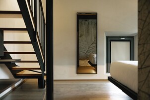 Quarto moderno com uma cama, um espelho grande e uma escada.