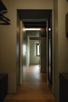 Um corredor estreito com soalho de madeira e uma porta no final.