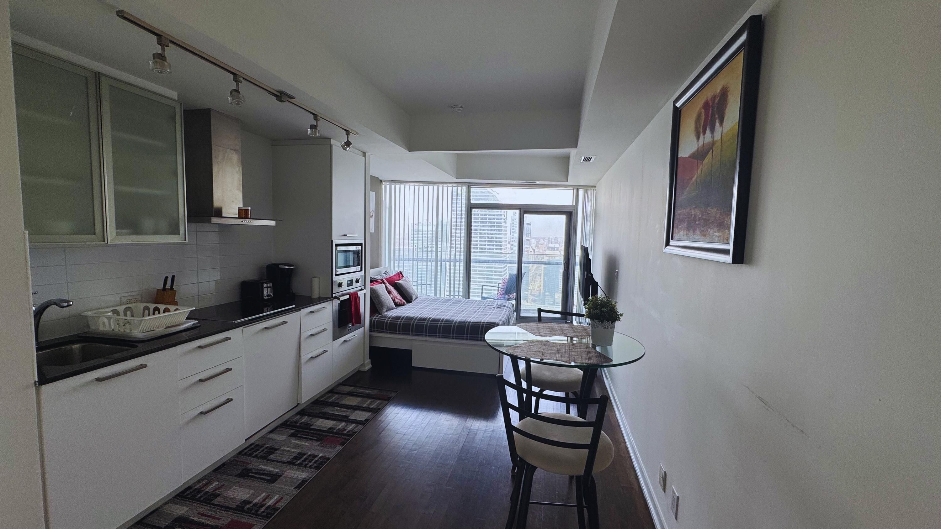 Cozinha compacta com área de refeições, uma cama e uma janela grande com vista para a cidade.