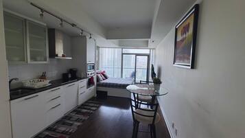 Cozinha compacta com área de refeições, uma cama e uma janela grande com vista para a cidade.