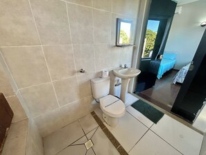 Casa de banho com sanita, lavatório e espelho pequeno.